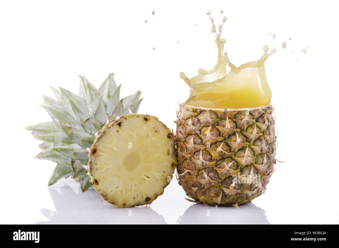 fresh yellow juice splashing from a sliced pineapple isolated on white ...