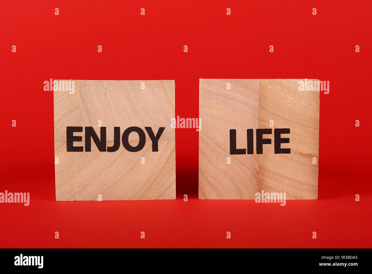 Close up two wooden cube signs with ENJOY LIFE words over red ...