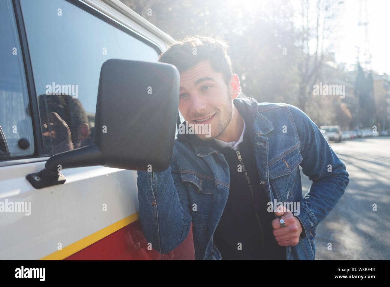 Vain man checking his looks in the mirror of his van Stock Photo - Alamy