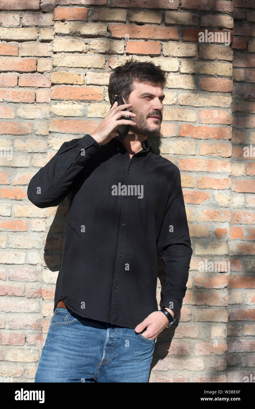 Young man making phone call walking on the street Stock Photo - Alamy