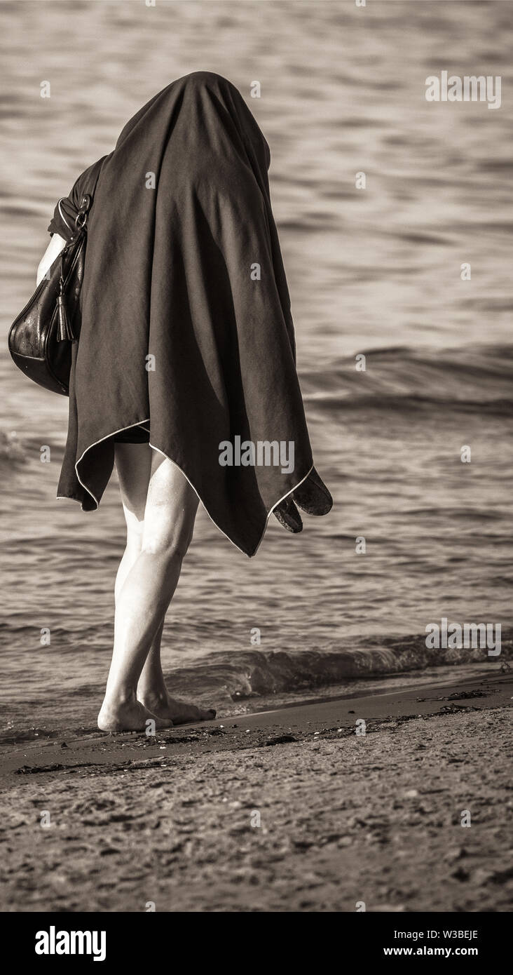 woman hiding from the sun on beach Stock Photo - Alamy