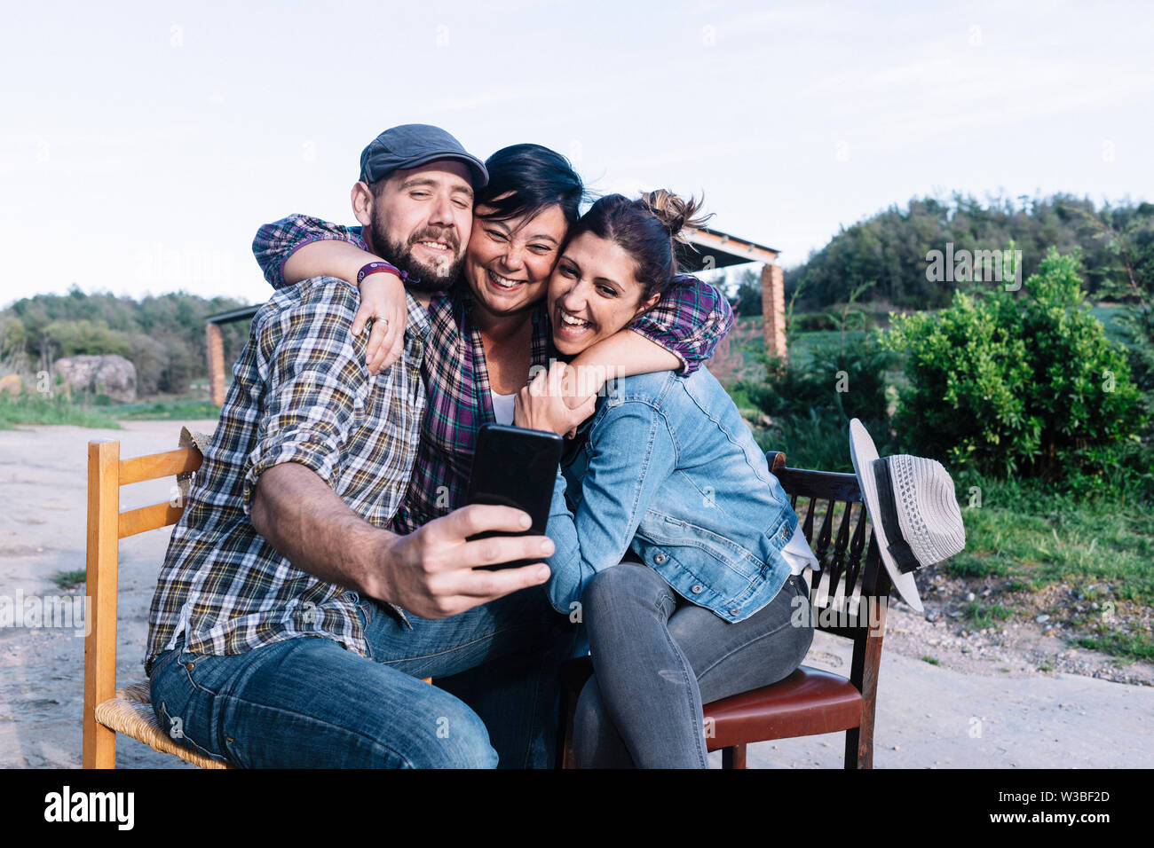 A group of friends sitting outdoors while taking a selfie with friends ...