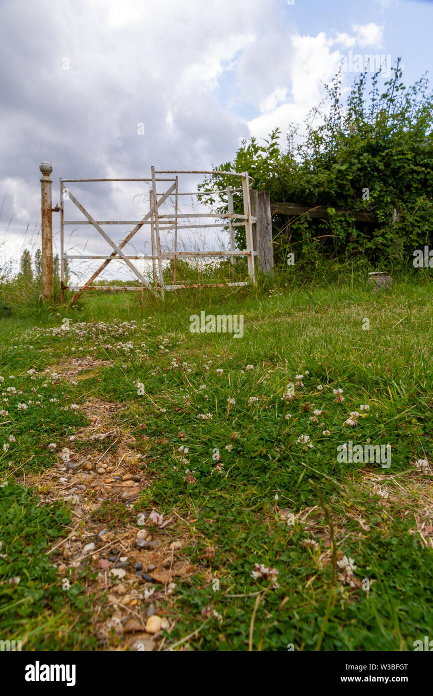 looking along a path towards an old gate in a hedgerow Stock Photo - Alamy