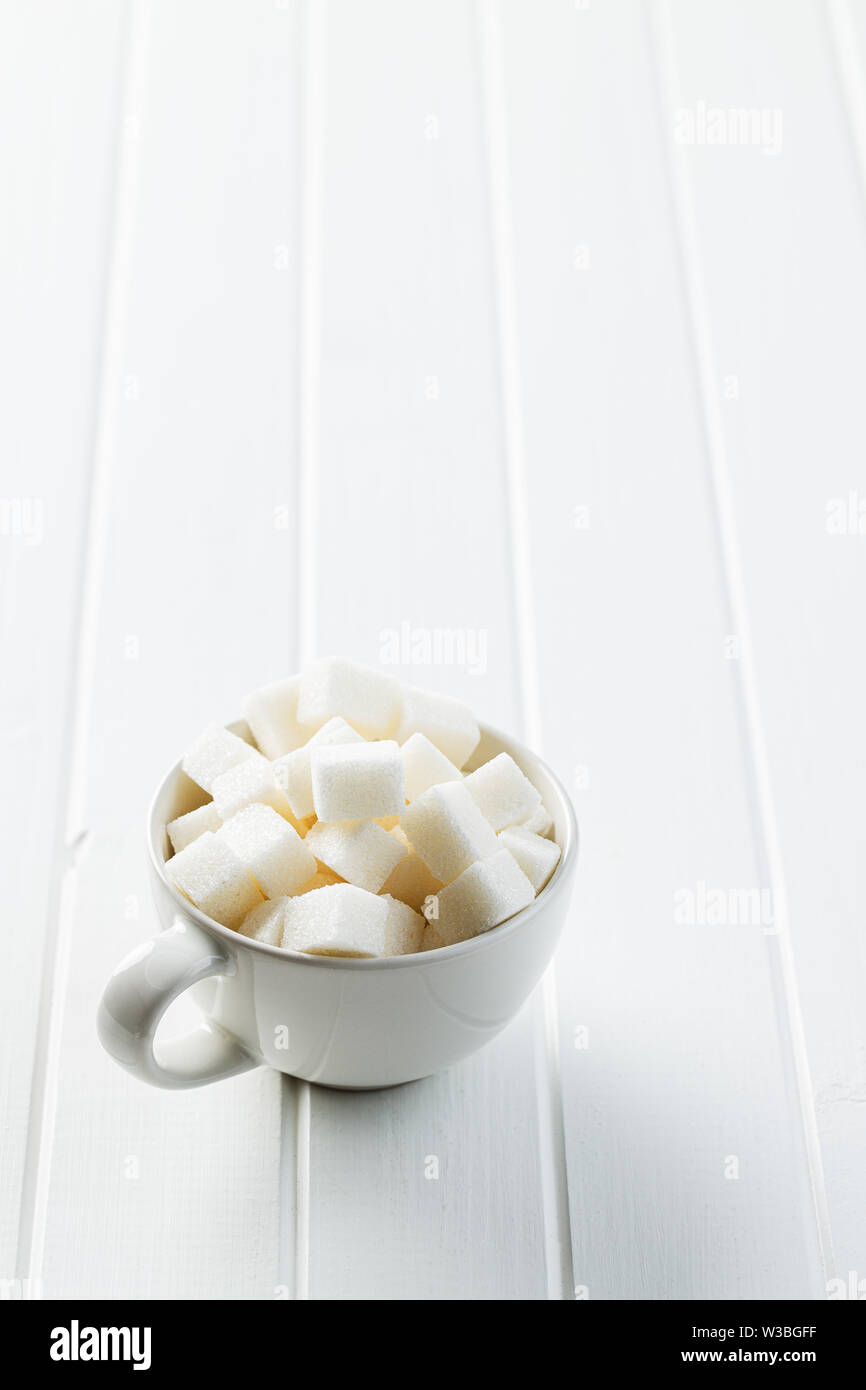 Sweet sugar cubes in mug on white table Stock Photo - Alamy