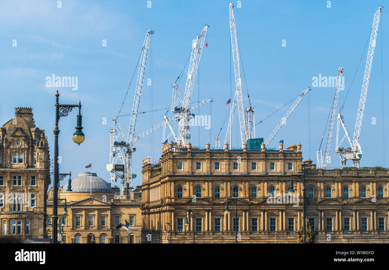 Construction cranes behind the sunlit, historic architecture of ...