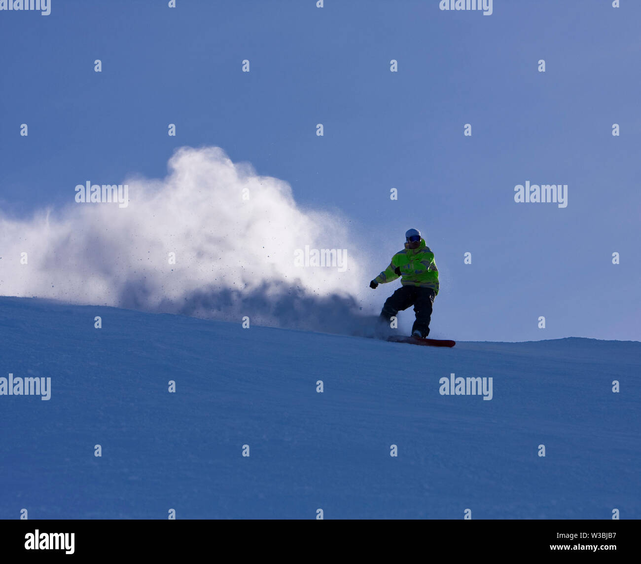 A snowboarder carving a turn at Whistler creates a huge spray of snow ...
