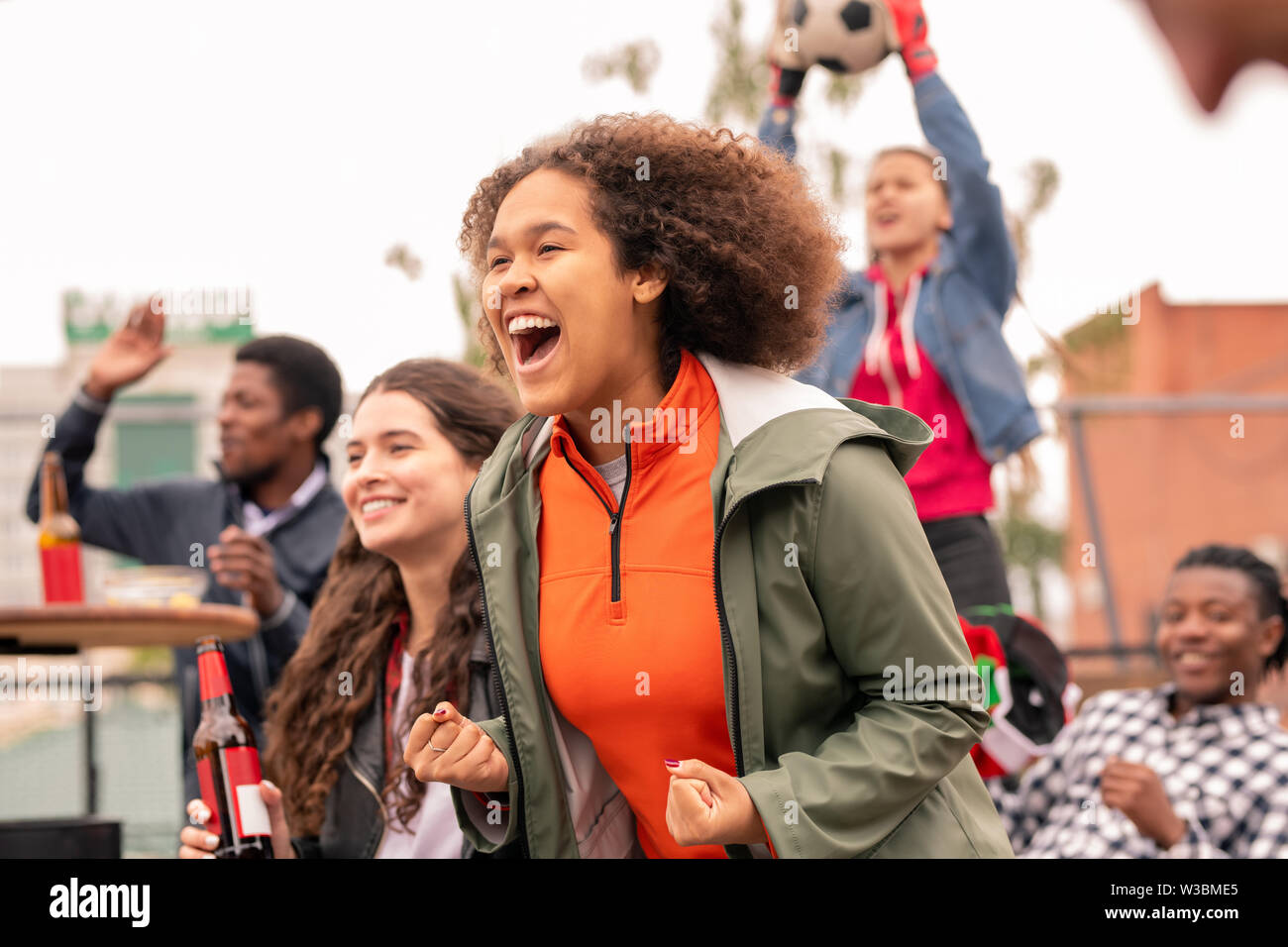 Ecstatic intercultural friends cheering for their football team after ...