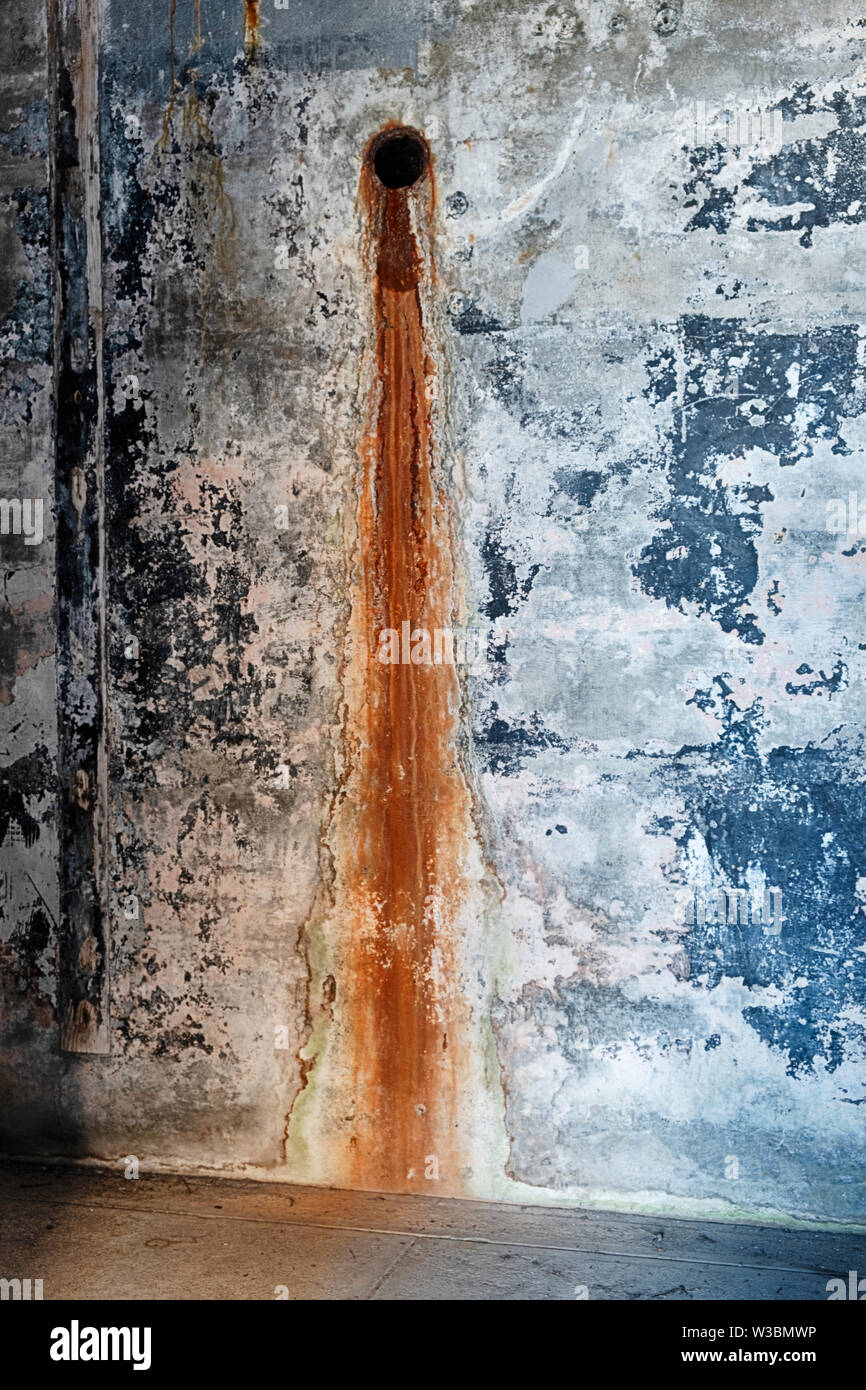 On old pipe has created a rusty water stain on a concrete wall inside ...