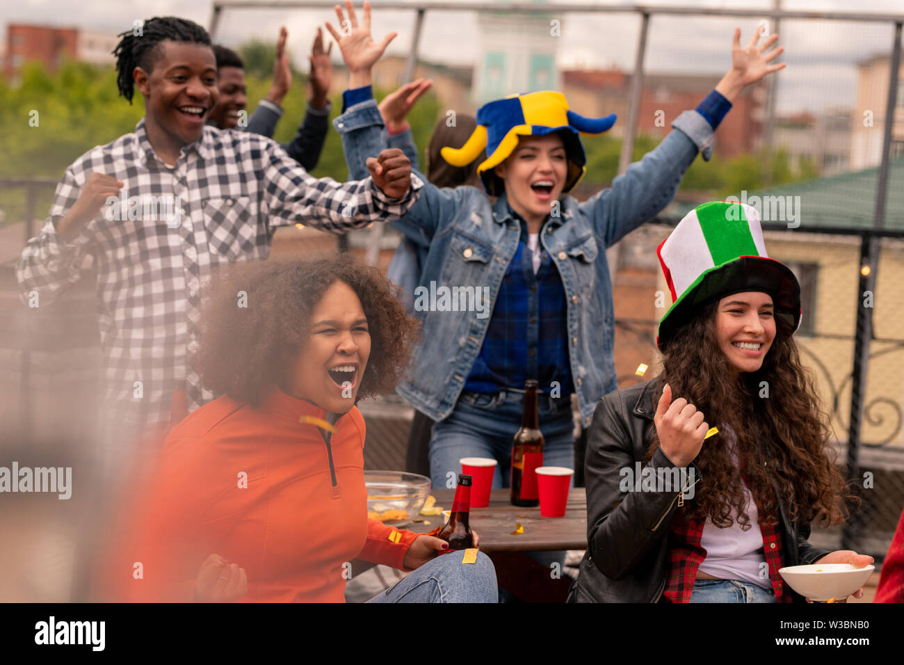 Three happy girls and guy cheering for their team during broadcast ...