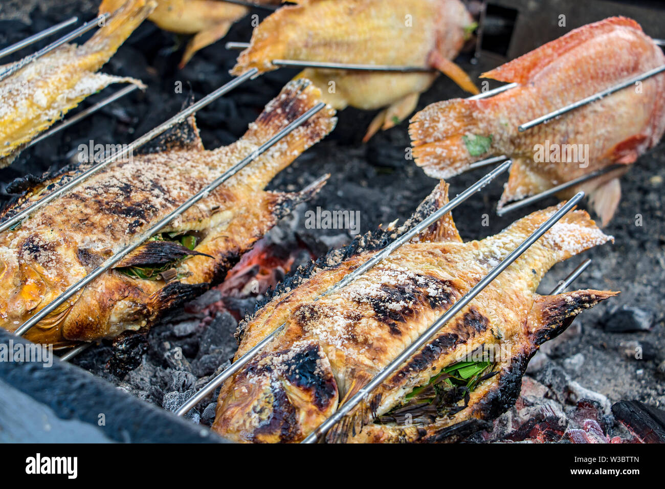 Grilling fish over coal, street restaurant, Thailand. Preparing roasted ...