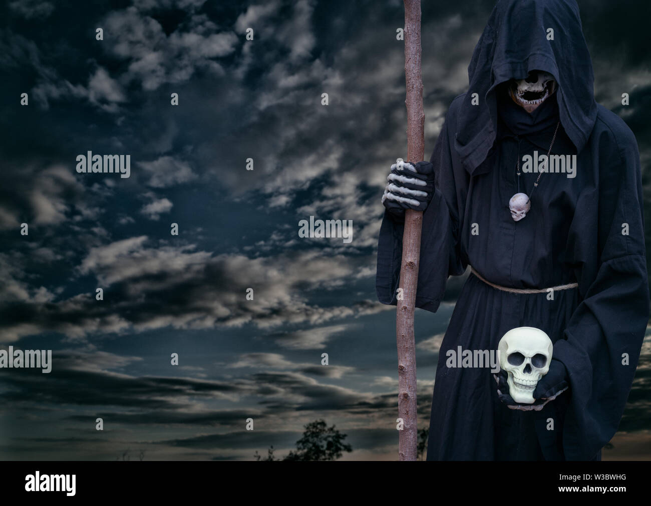 Grim reaper holds a skull in his hand, on a dark night sky Stock Photo ...