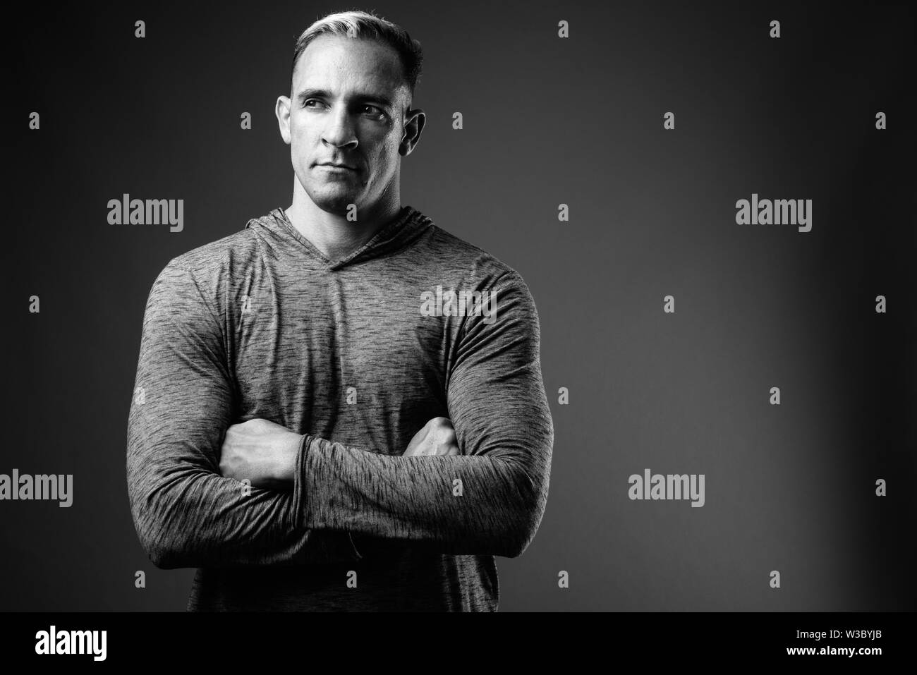 Studio shot of muscular man wearing gray long sleeved hooded shirt in ...
