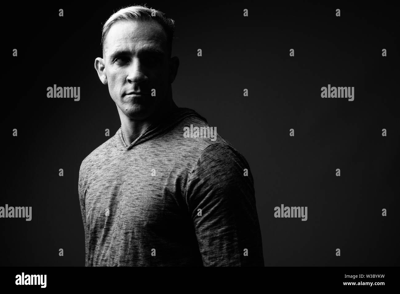 Studio shot of muscular man wearing gray long sleeved hooded shirt in ...