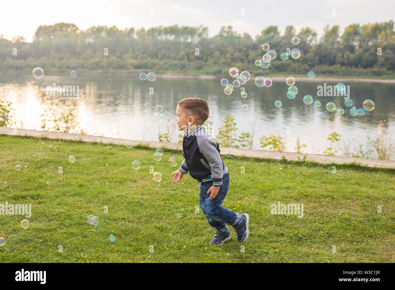 Children and nature concept - Boy trying to catch soap bubbles Stock ...