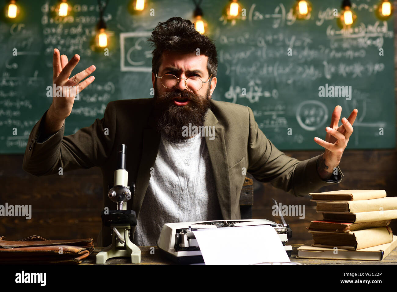 Angry scientist work at desk. Bearded man with books and retro ...