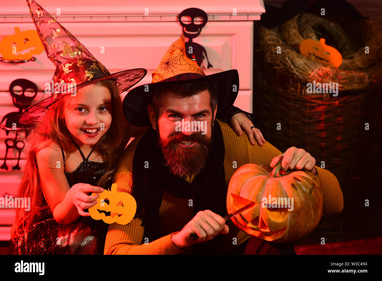 Wizard and little witch with Halloween decor. Girl and bearded man with ...