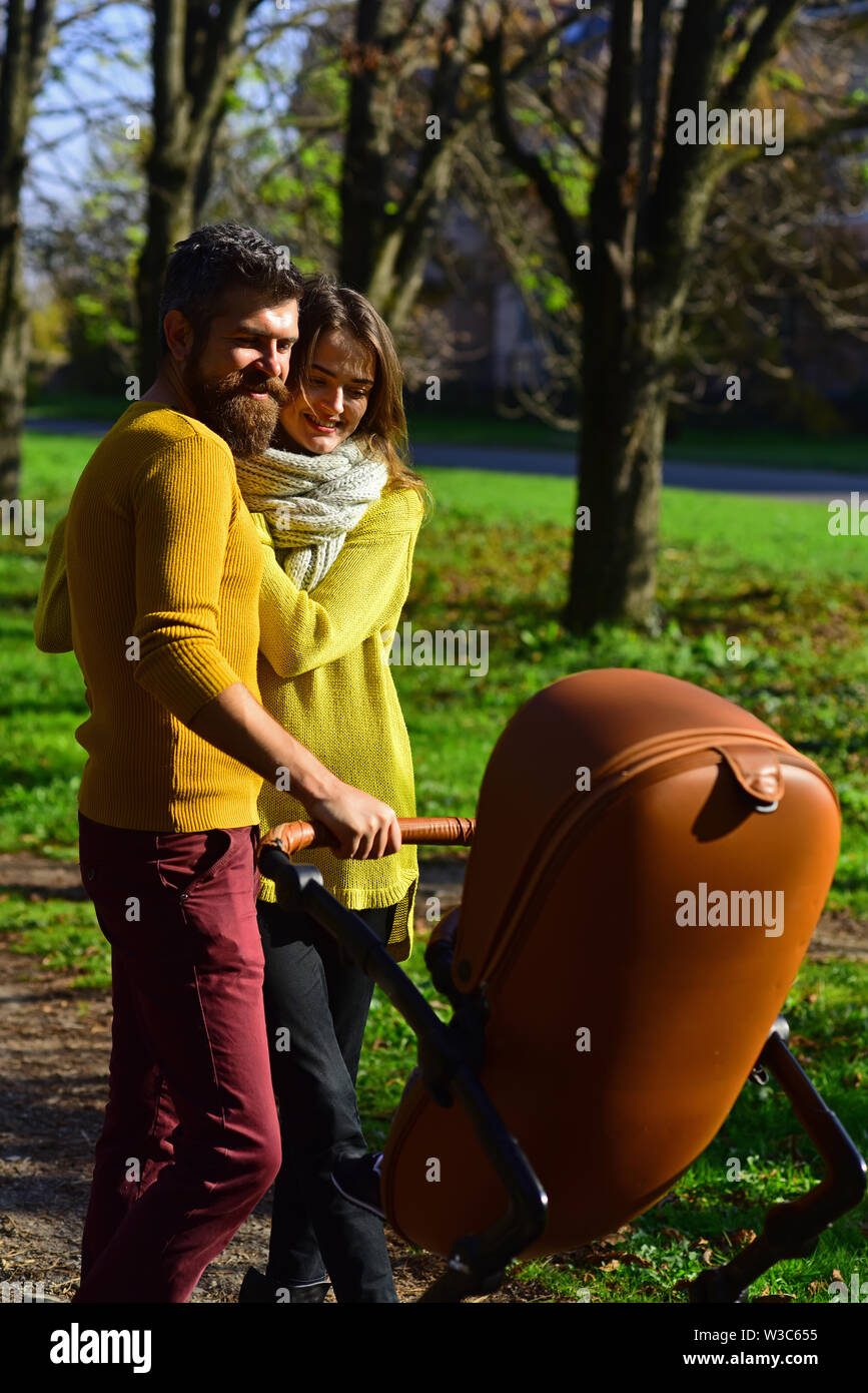 Happy parents enjoy parenthood. Parents stroll baby pram in sunny park ...