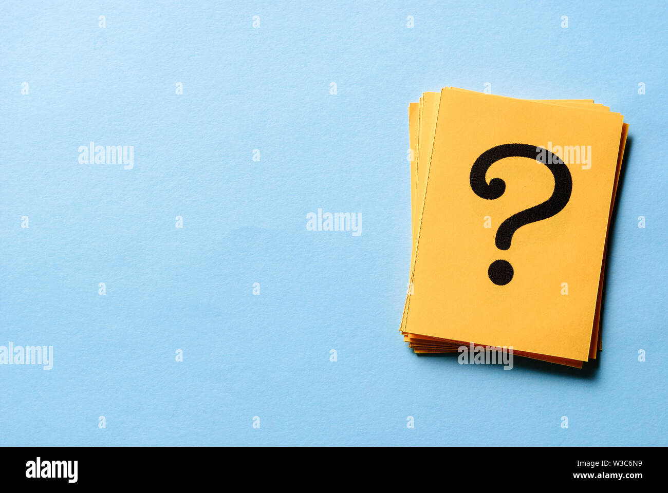 Stack of question marks on yellow cards arranged to the side on blue ...