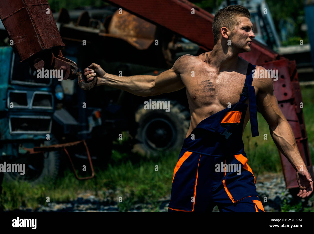 Muscle concept. Muscle man in working uniform pull heavy iron crane ...