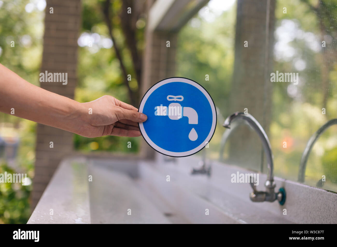 Male hands holding a blue faucet sign with the tap water faucet in the ...