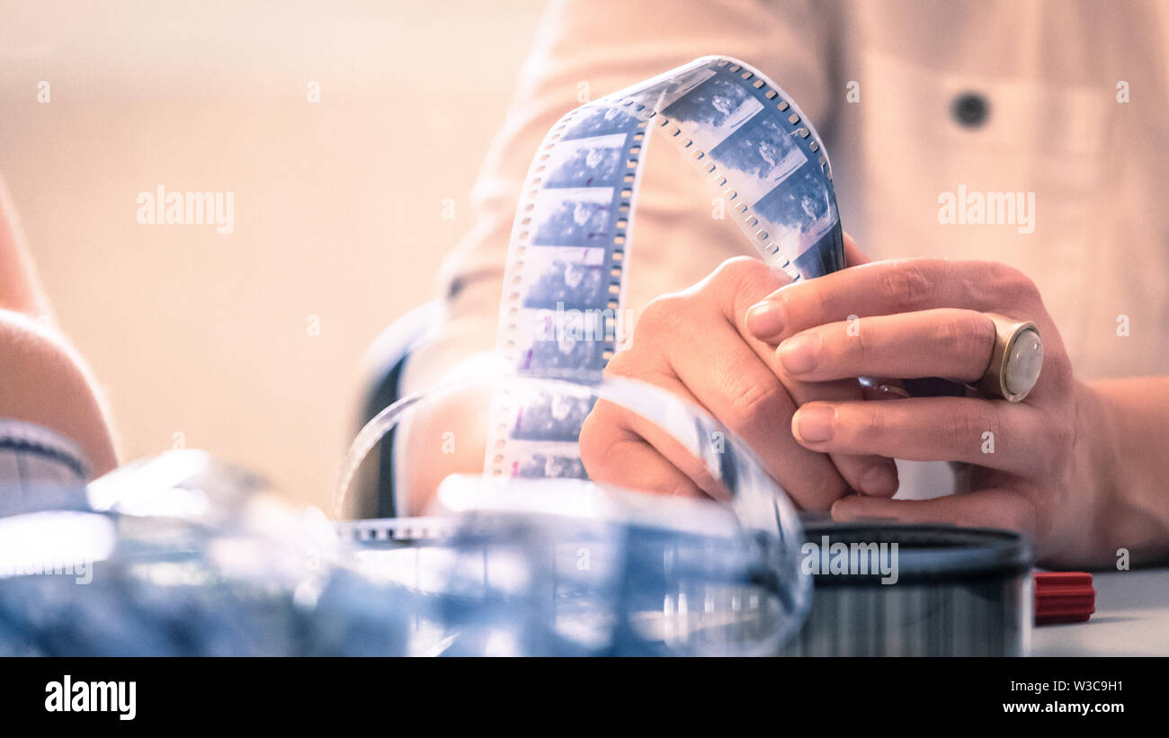 Filmmaker hands holding a film strip, cutting table Stock Photo - Alamy