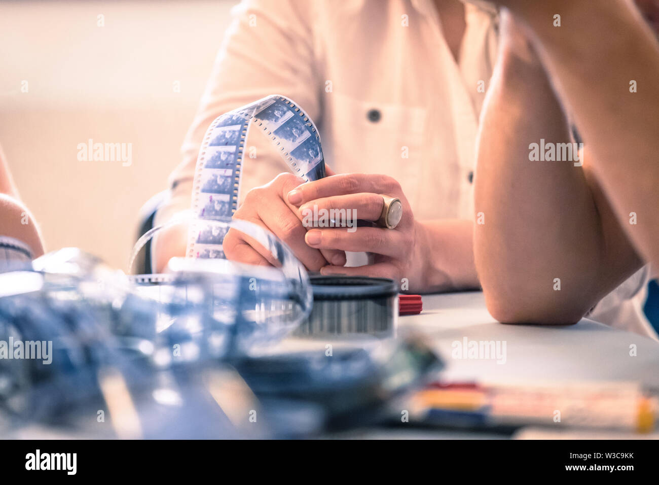 Filmmaker hands holding a film strip, cutting table Stock Photo - Alamy