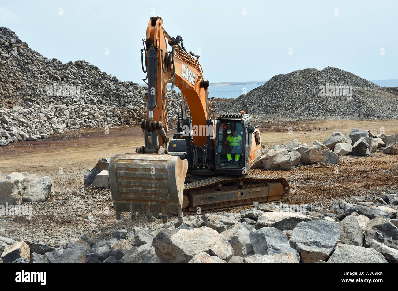 Digger moving large boulders on construction site Stock Photo - Alamy