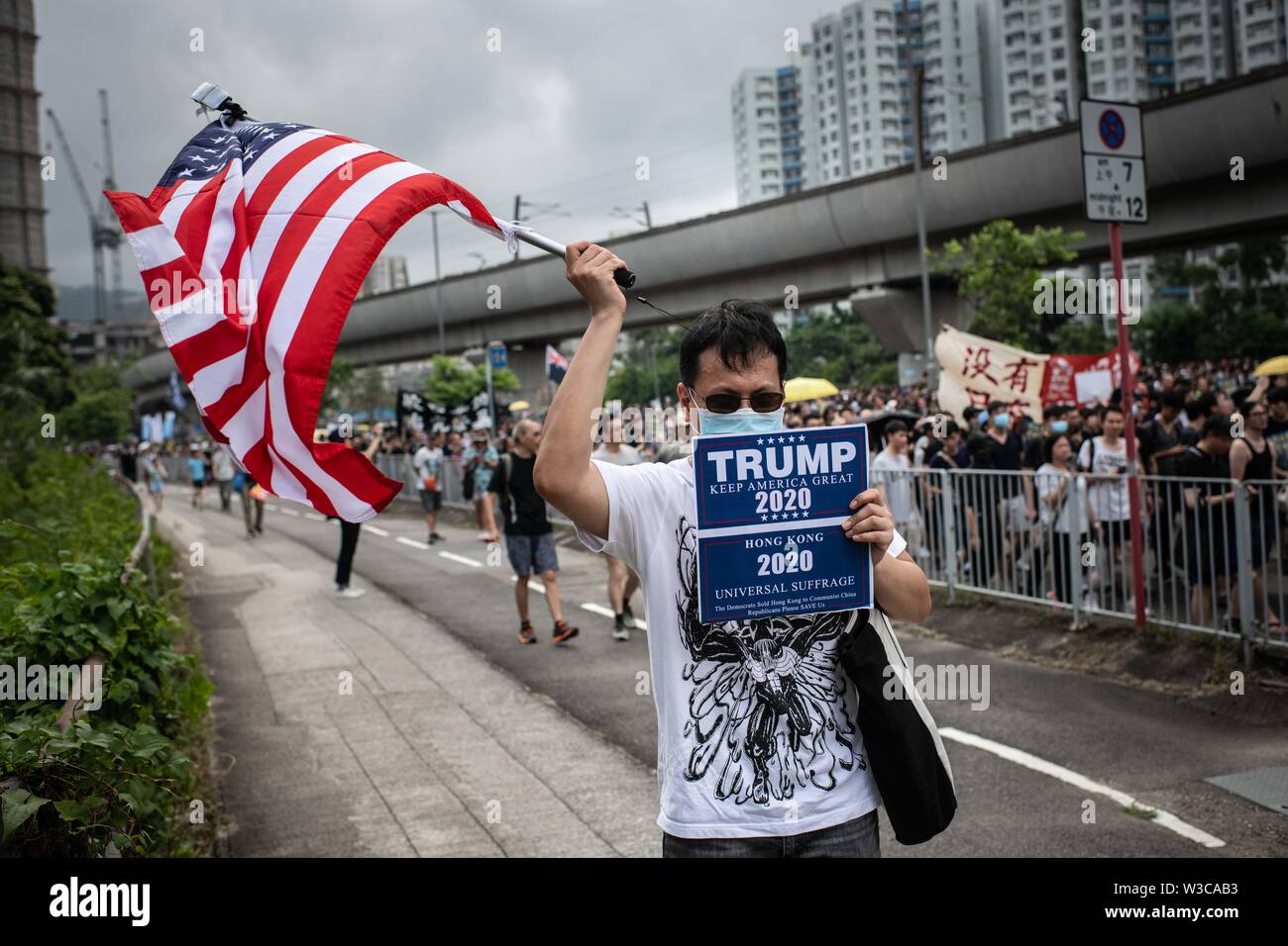 A man holds an American flag and pro Trump placard, during the ...