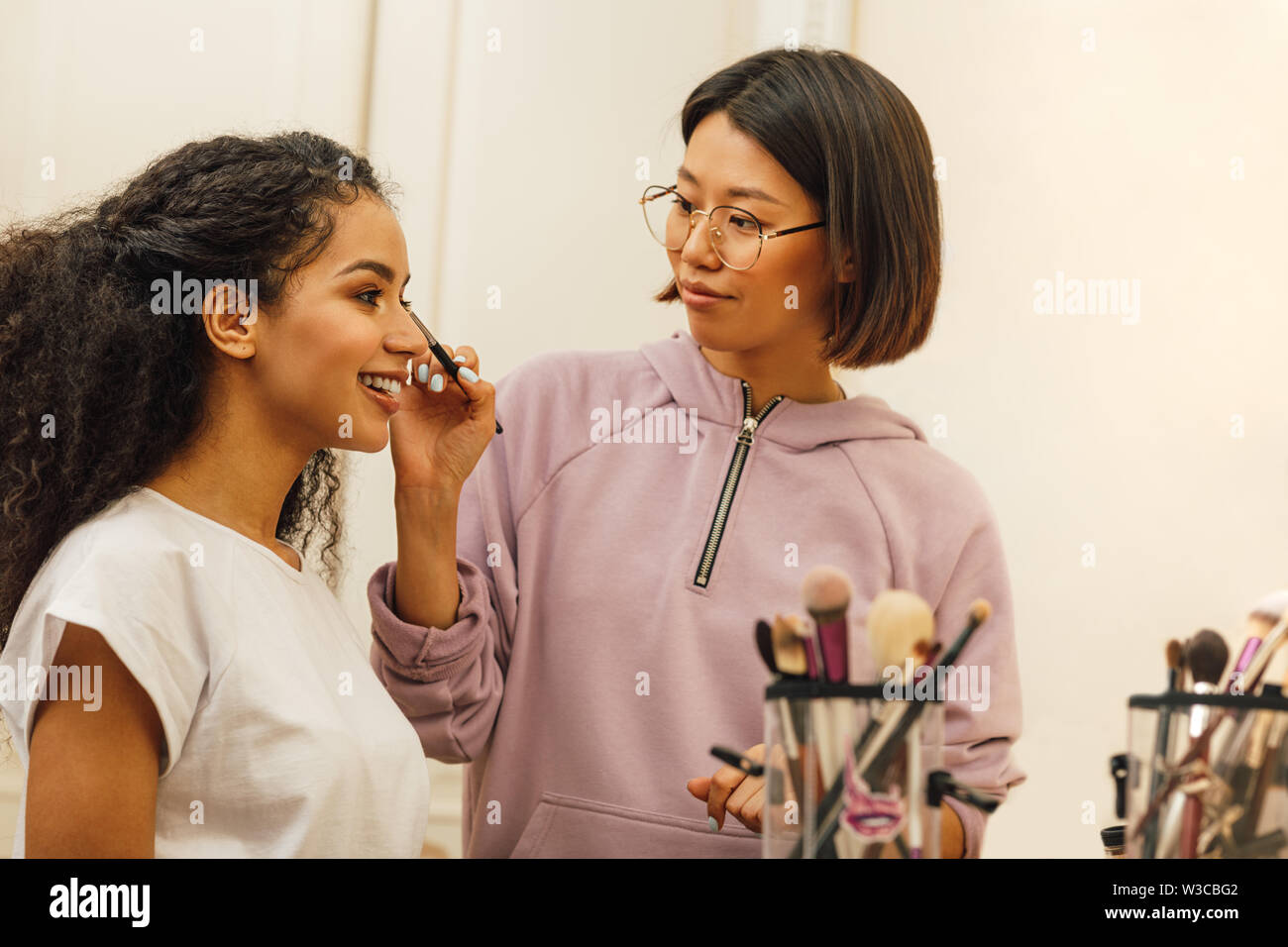 Makeup artist applying makeover on a model face in dressing room Stock ...