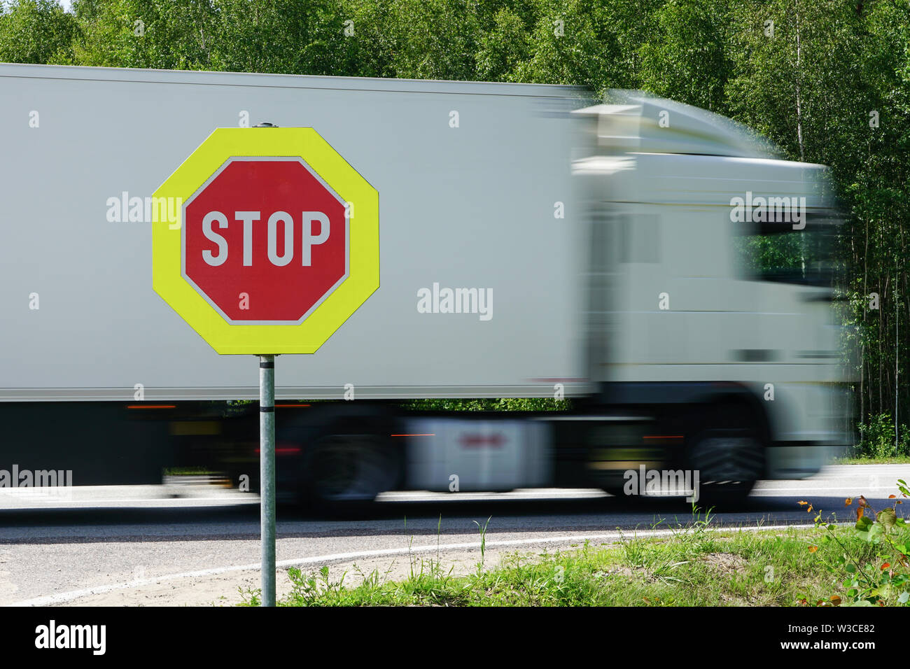 red stop road sign in the foreground and blurred fast truck in the ...