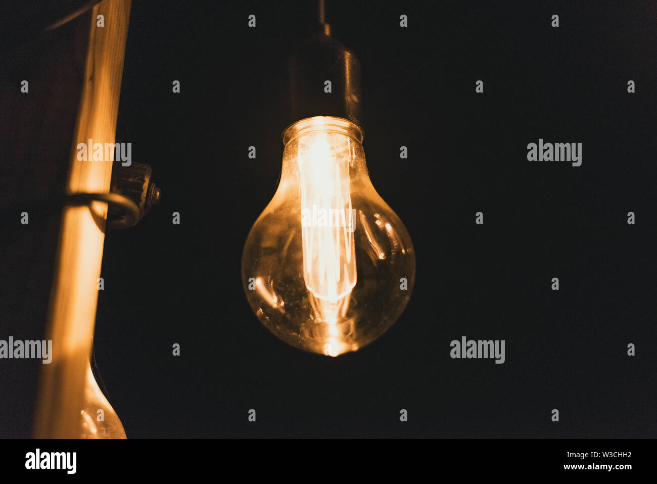 Yellow retro incandescent bulbs hang in the evening at a party. Light ...