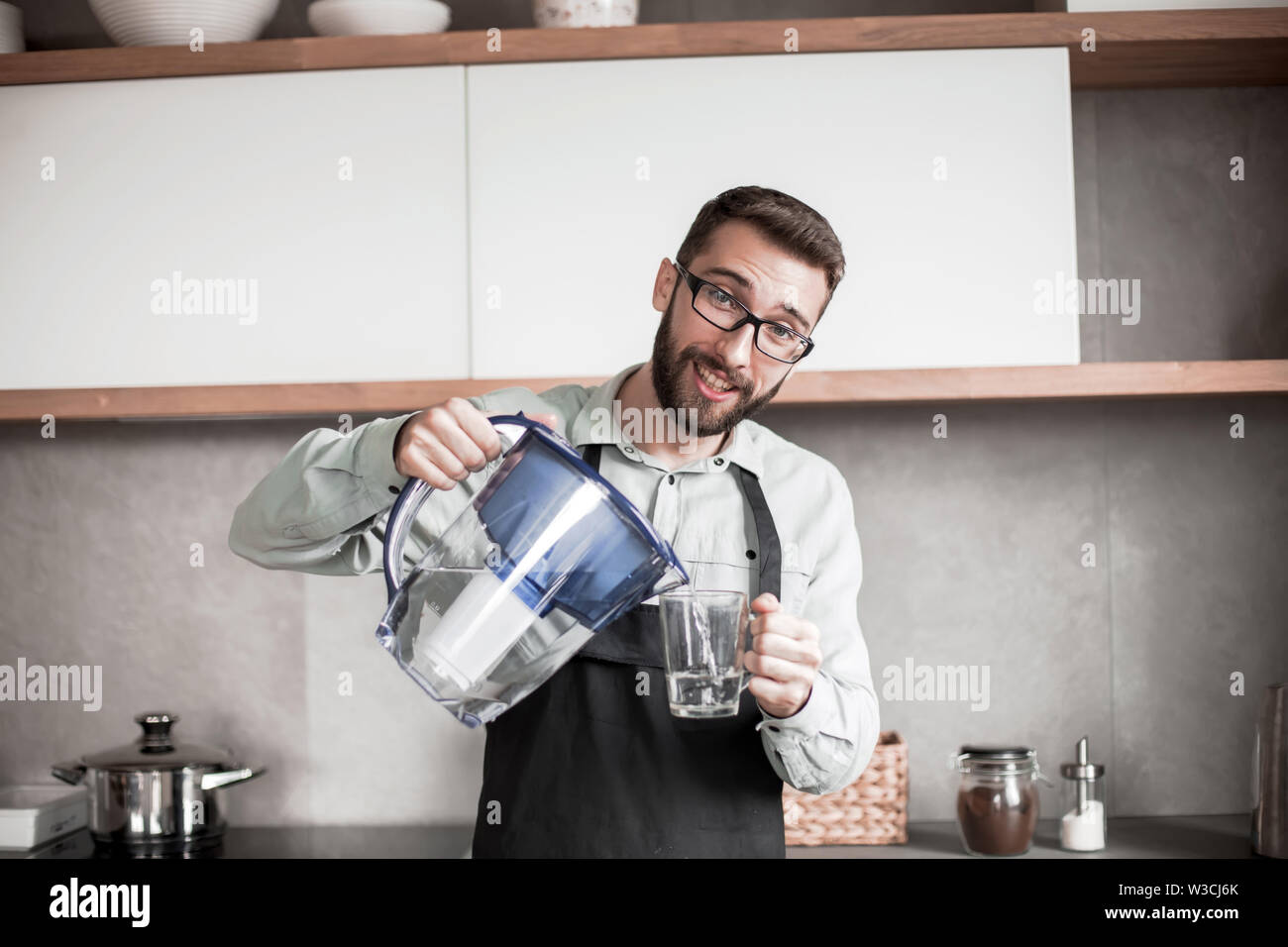 smiling man pouring clean water into a glass Stock Photo - Alamy