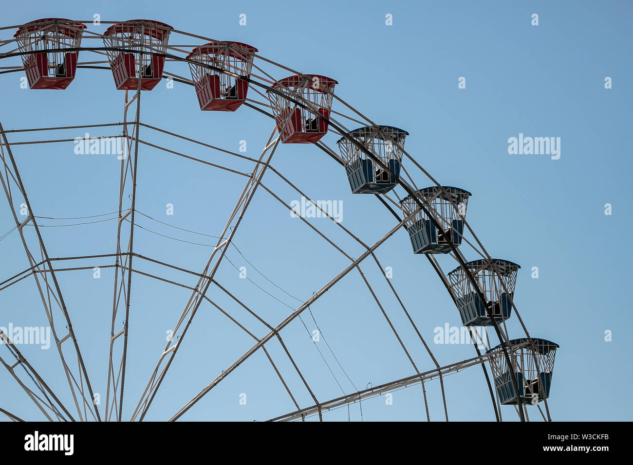 horizontal view of cabins of a ferris wheel on foreground whit the sky ...