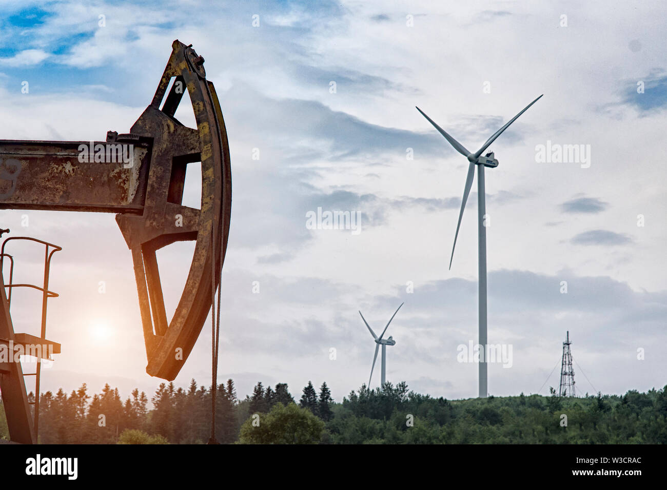 Operating oil and gas well, profiled on blue sky with clouds and wind ...