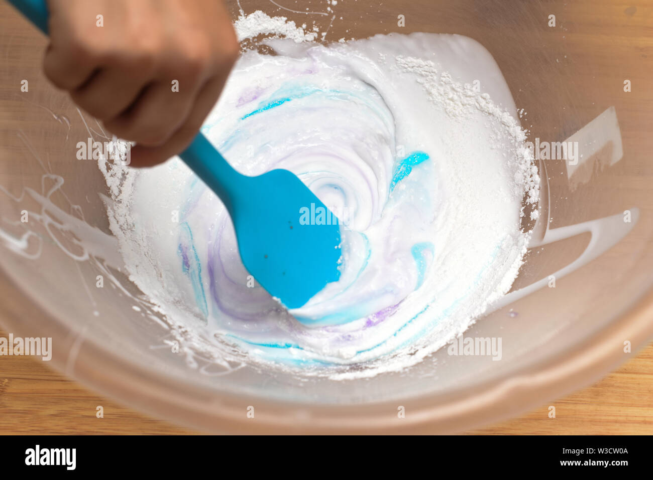 Children at home making homemade slime. Focus on hands mixing the ...
