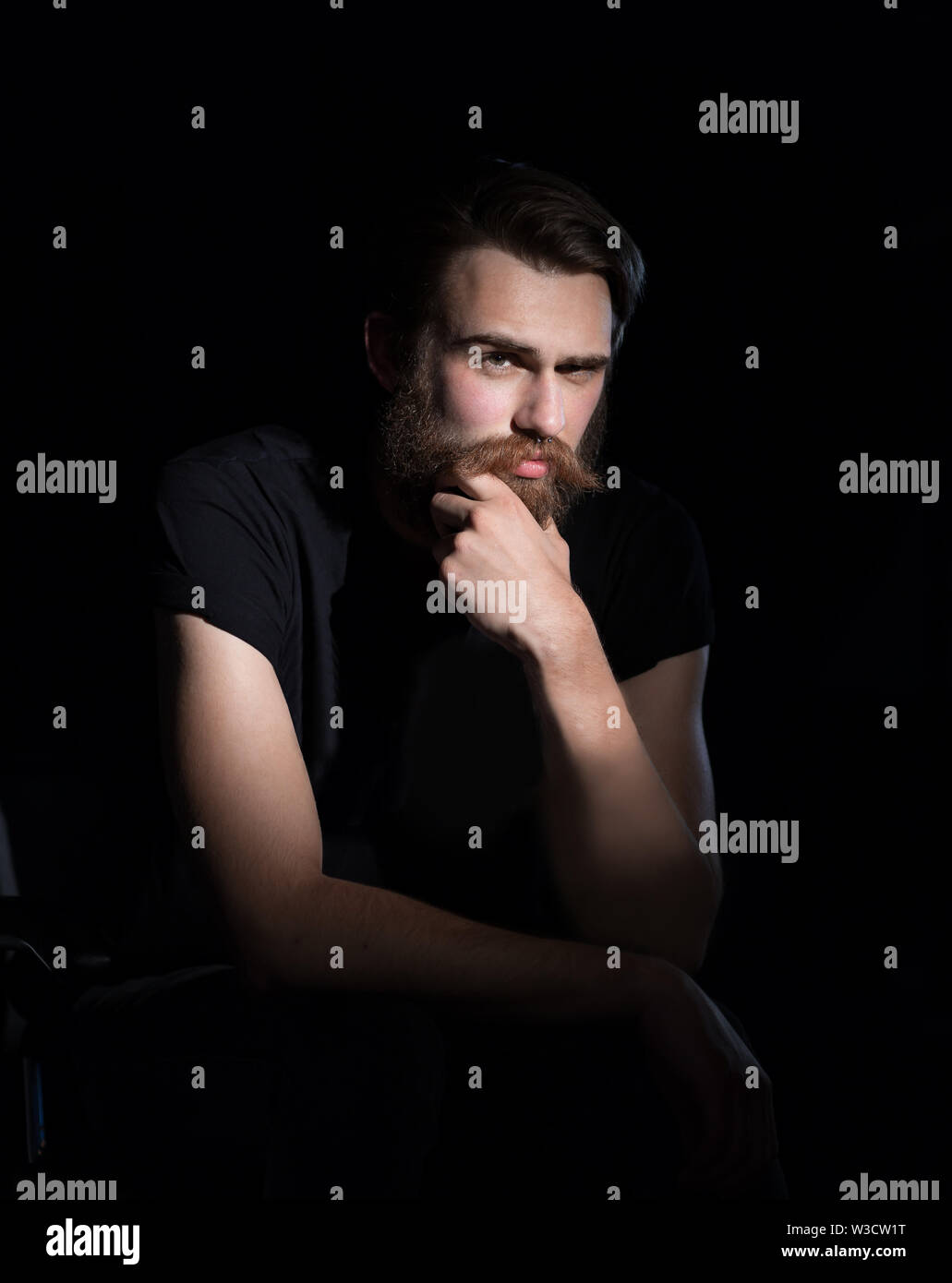 serious hipster man sitting in a chair. isolated on black background ...