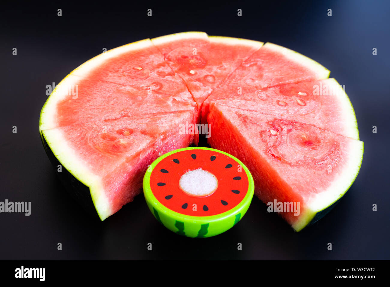 A large slice of watermelon divided into smaller pieces next to a ...