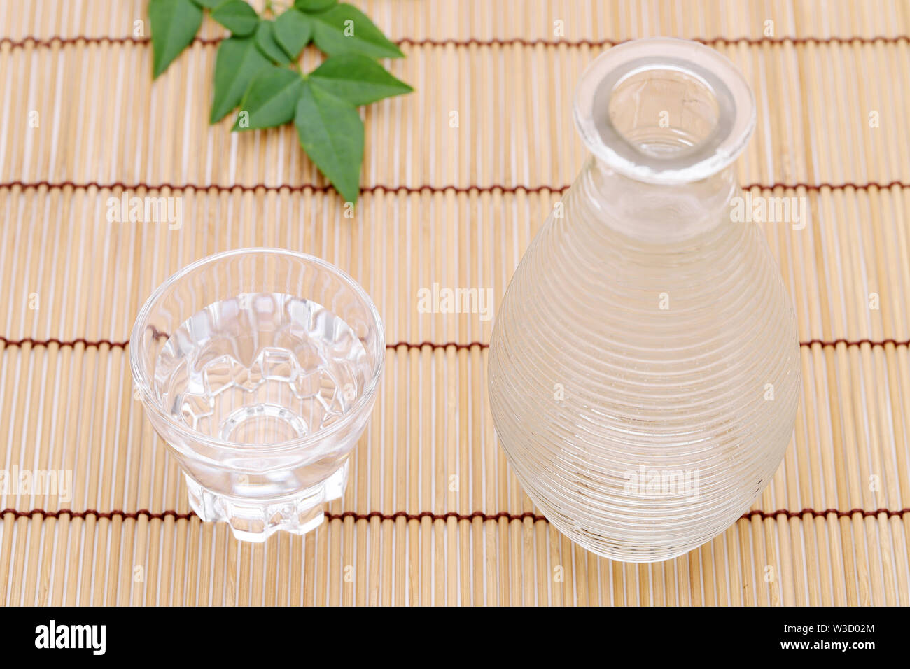 Japanese sake in transparent glass cup and jar on bamboo table Stock ...