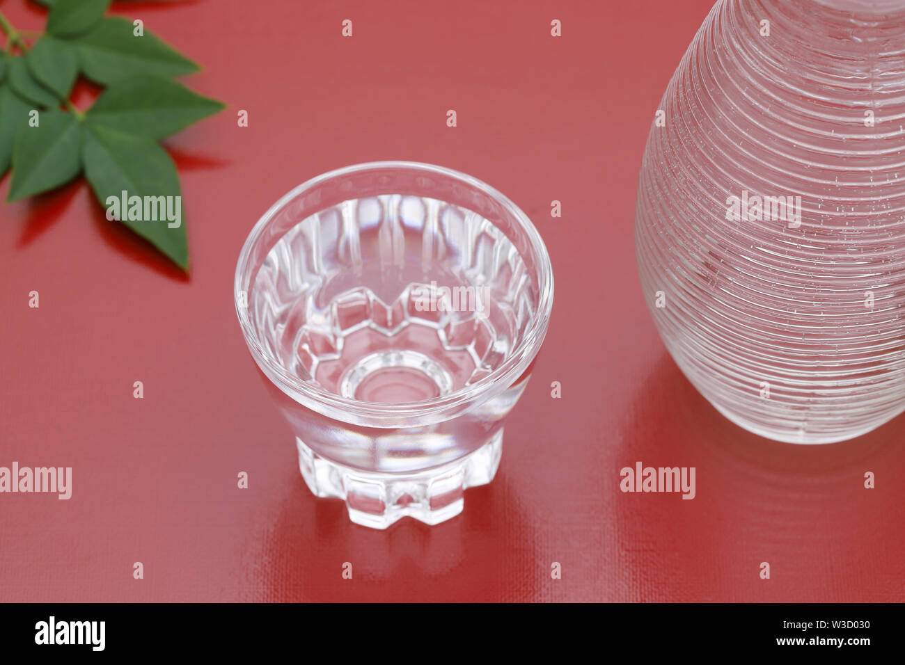 Japanese sake in transparent glass cup and jar on red background Stock ...