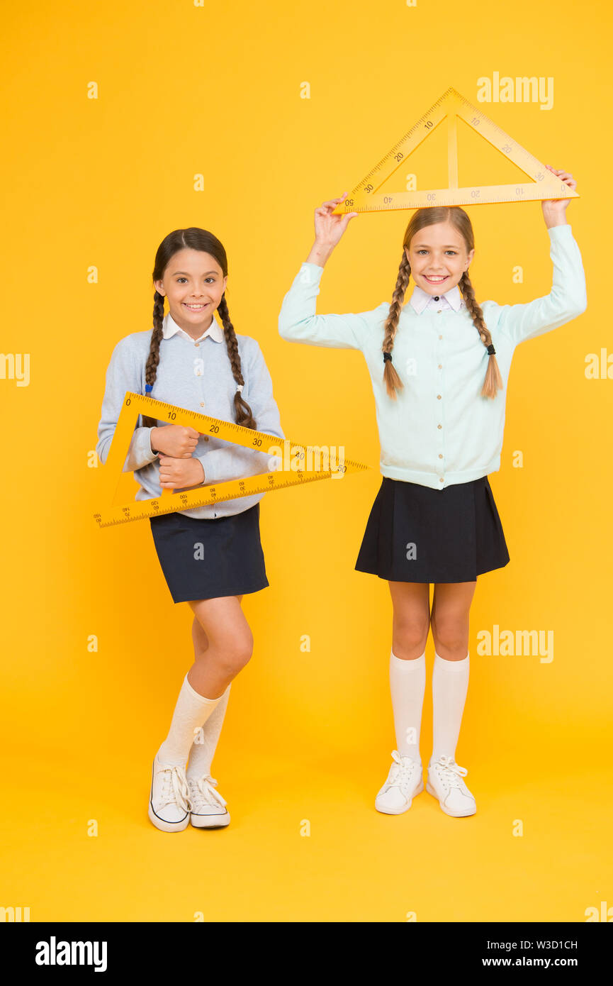 Measuring angles at geometry. Cute schoolgirls holding triangles for ...