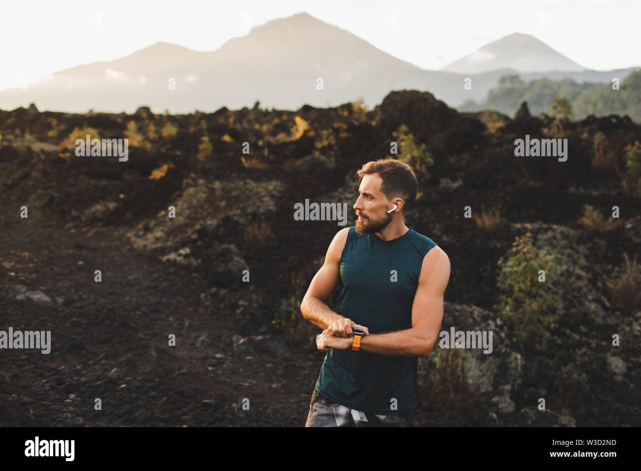 Young hipster runner with beard using smart watch and listening music ...