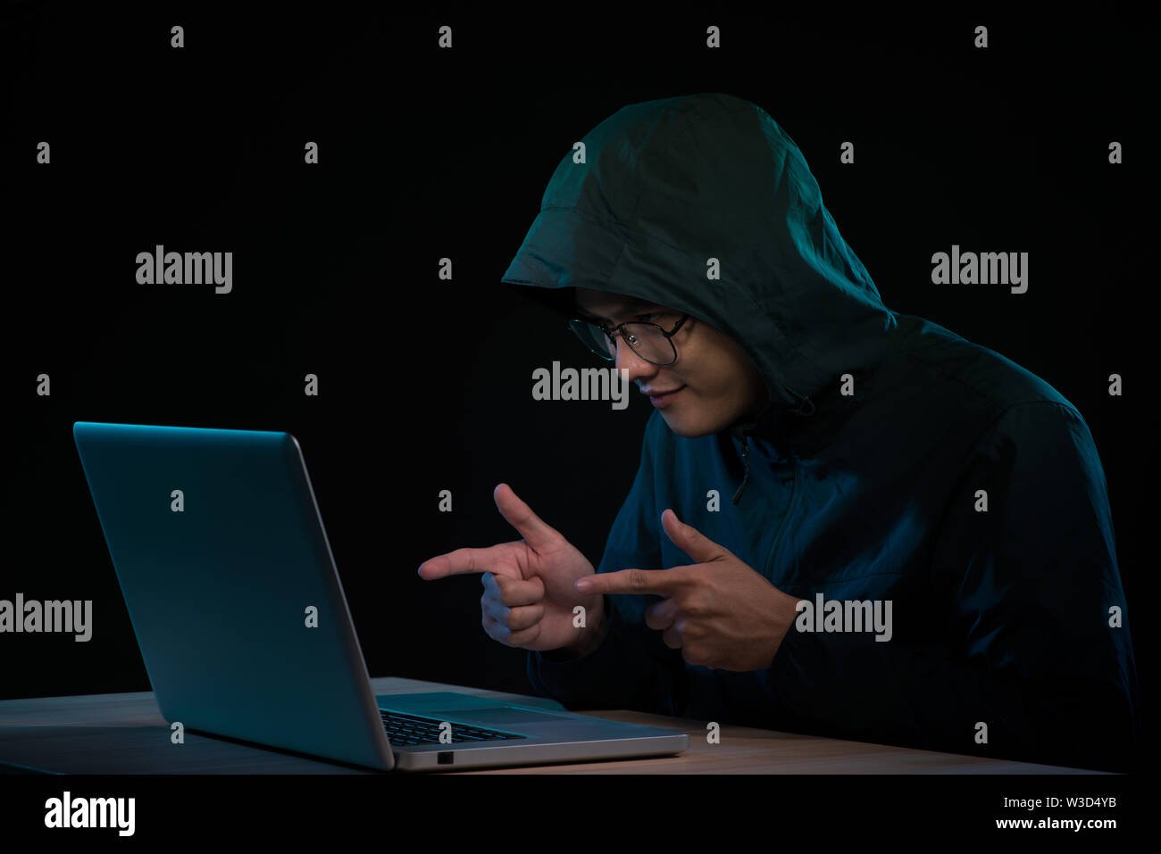 Successful male hacker poses in front of laptop computer, clenches ...