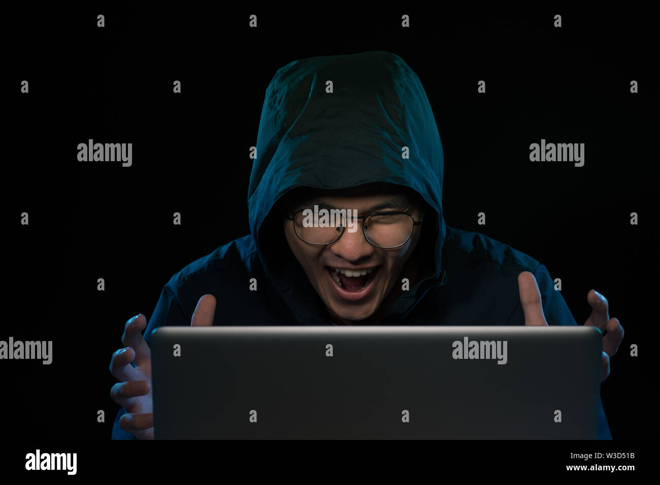 Successful male hacker poses in front of laptop computer, clenches ...