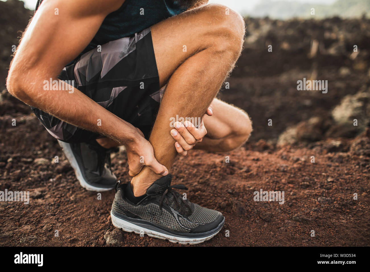 Achilles injury on running outdoors. Man holding Achilles tendon by ...