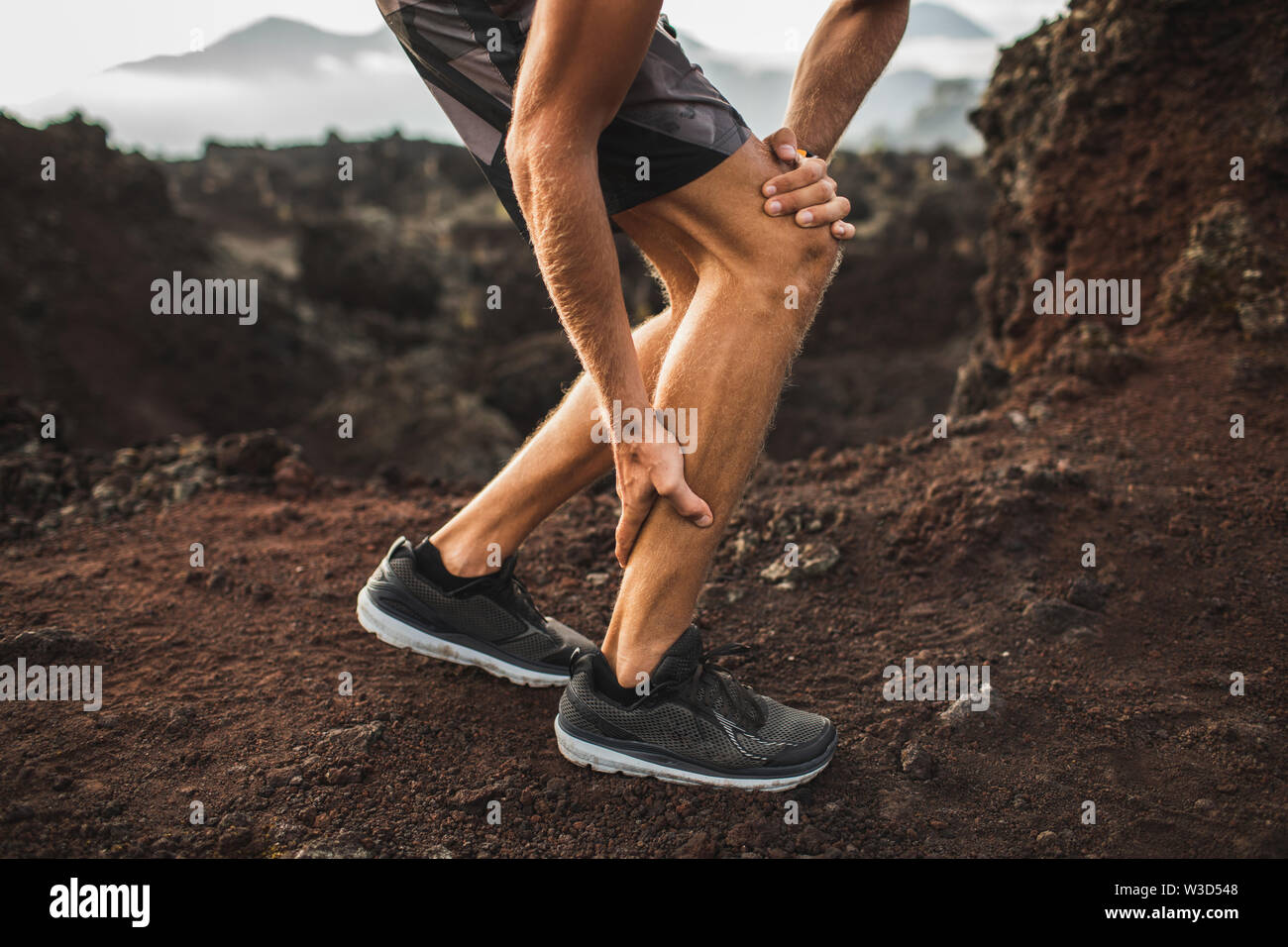 Male runner holding injured calf muscle and suffering with pain. Sprain ...