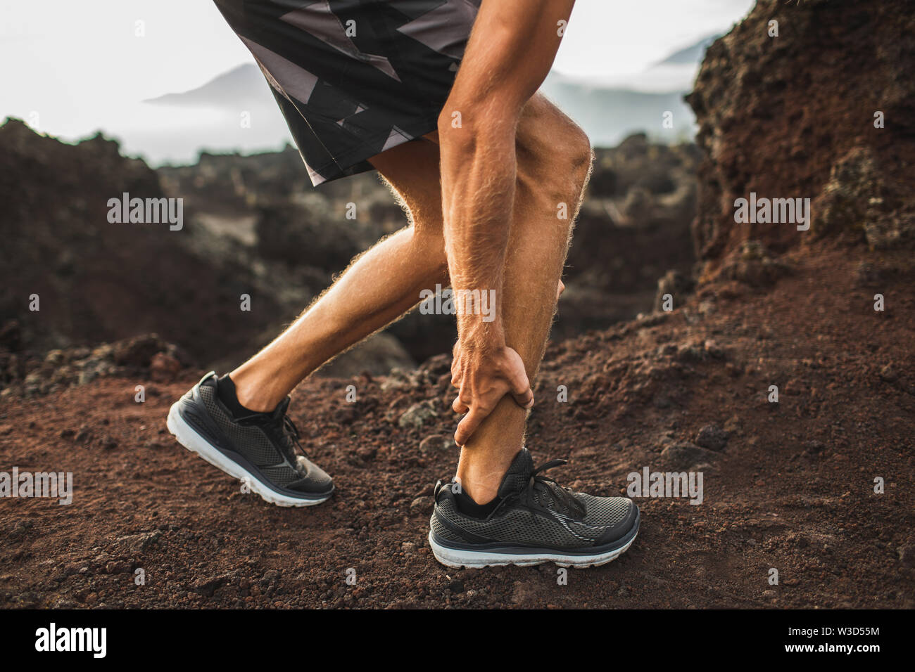 Male runner holding injured calf muscle and suffering with pain. Sprain ...