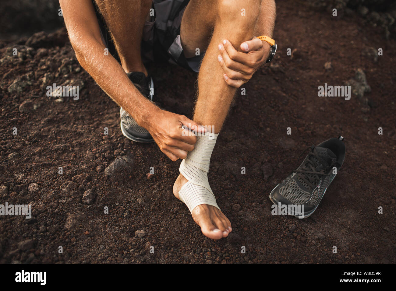 Man bandaging injured ankle. Injury leg while running outdoors. First ...