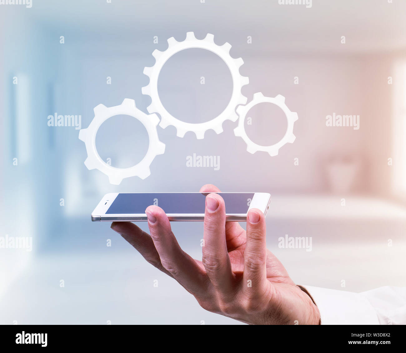 Hand of businessman holding smartphone with cogwheels over office background Stock Photo - Alamy