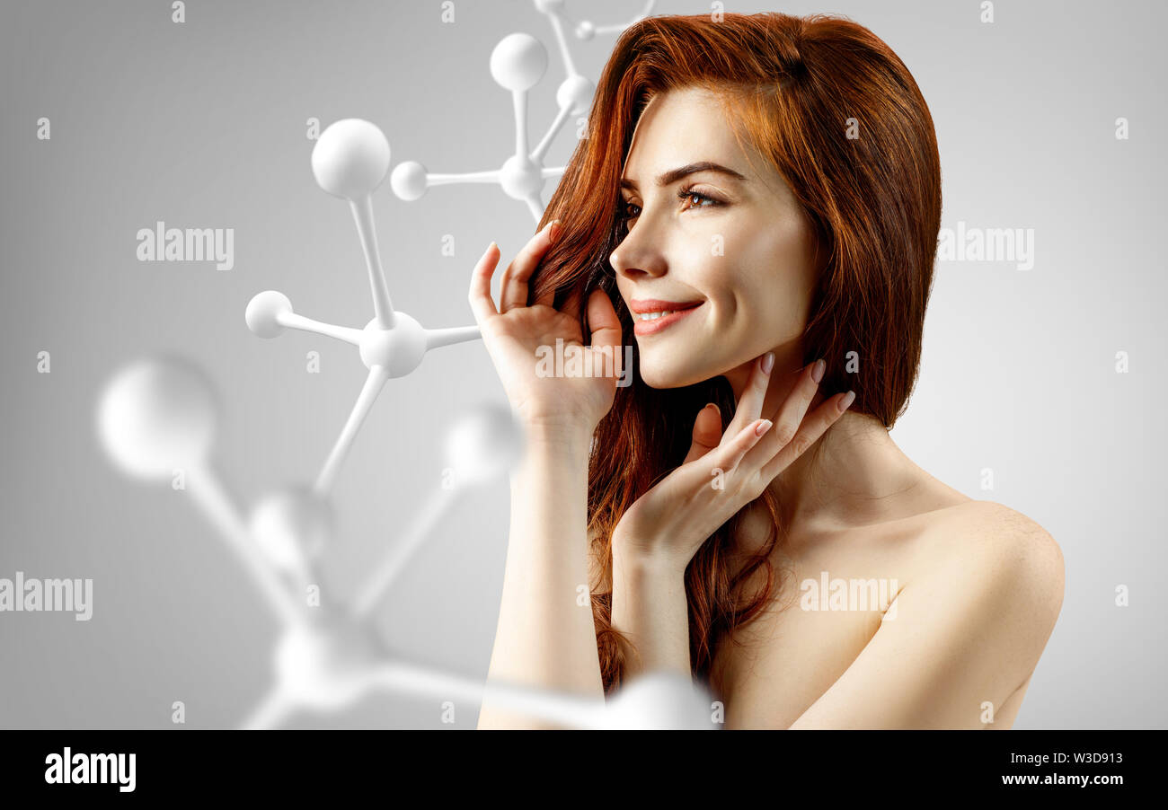 Beautiful redhead woman near big white molecule structure. Over gray ...