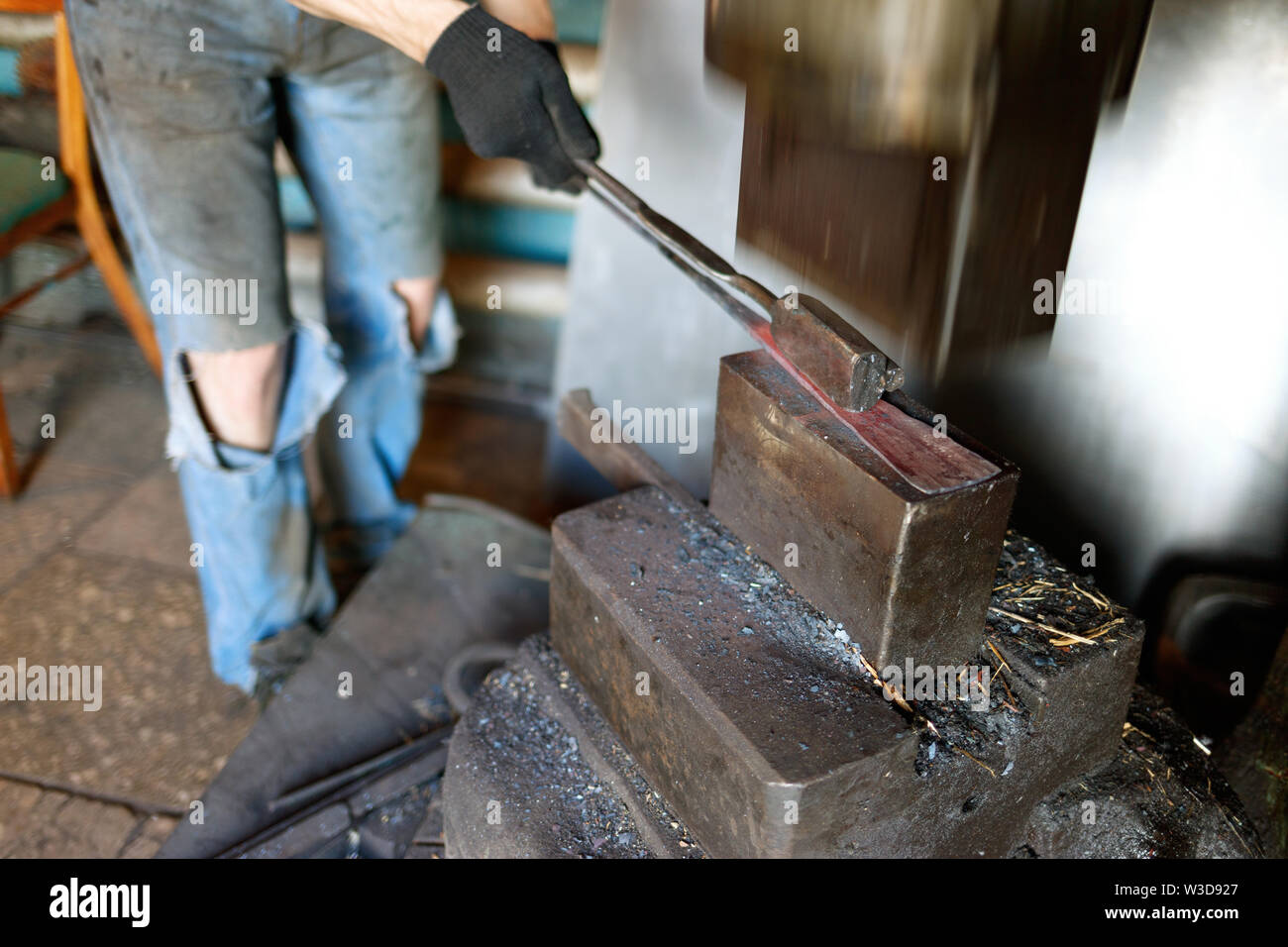 Unrecognizable blacksmith holding candent iron ingot and forging it ...